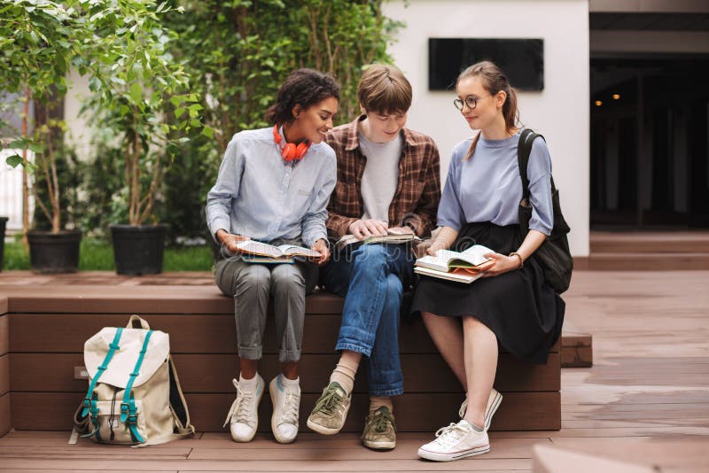 Group of Smiling Students Sitting on Bench and Reading Books in ...