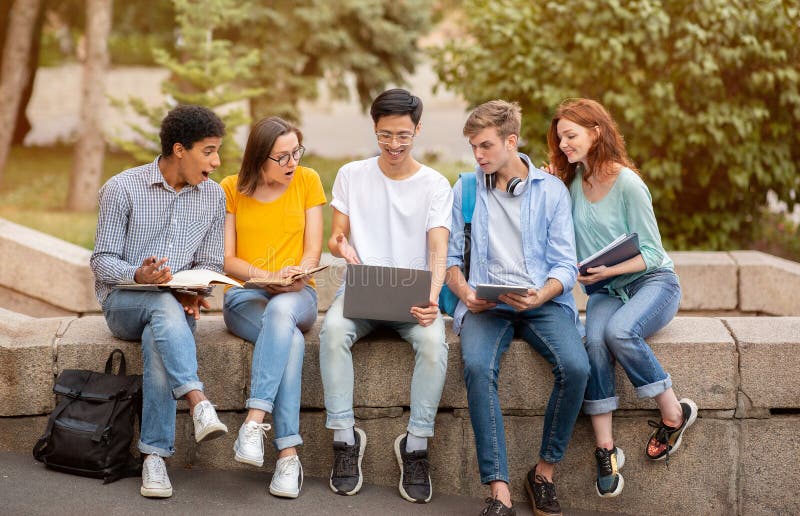 Group of Students Learning Together Using Laptop Sitting Outdoors Stock ...