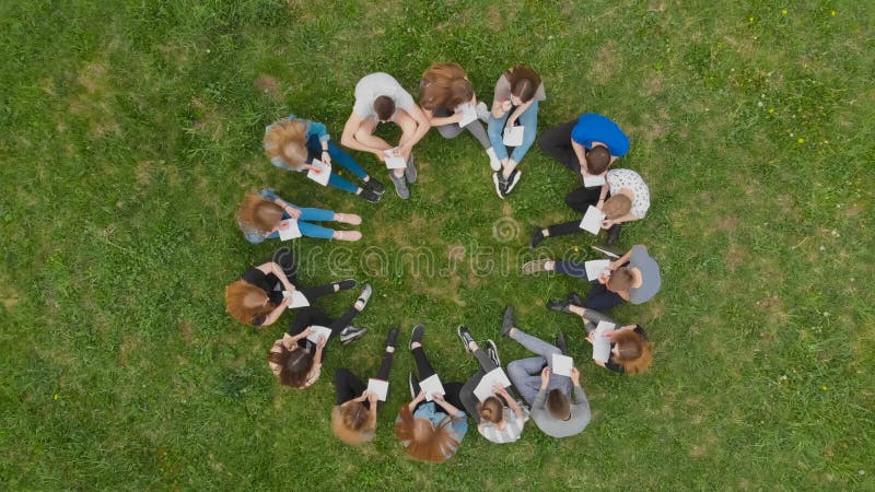 A Group of Students are Sitting in a Circle and Books on the Grass ...