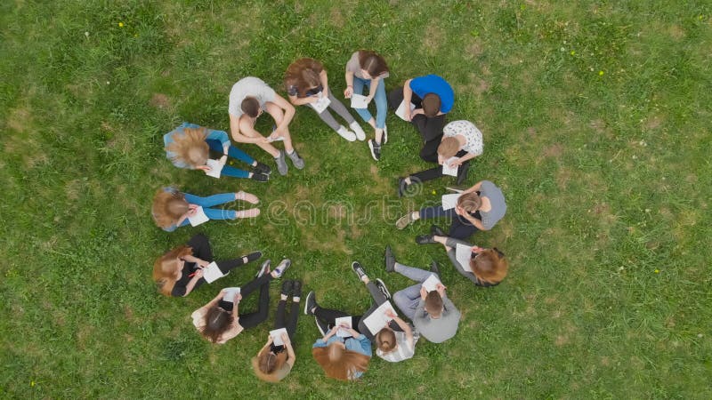 A Group of Students are Sitting in a Circle and Books on the Grass ...