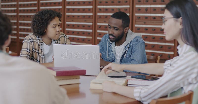 Group of Students Studying Together Using Laptop Talking Looking at ...