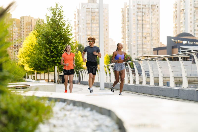Group of Three Active People Running Together Outdoors on Bridge Stock ...