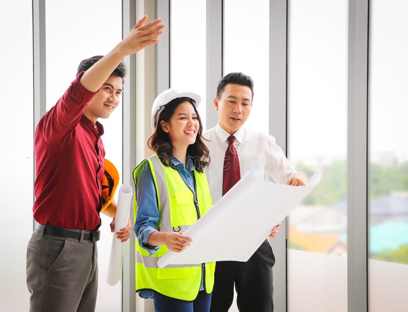 Three Construction Workers, One Woman and Two Men Standing by Windows ...