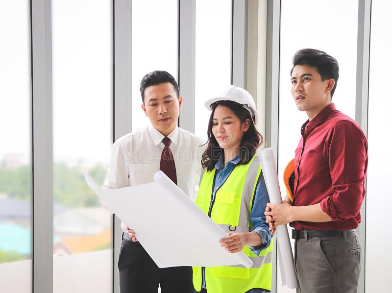 Three Construction Workers, One Woman and Two Men Standing by Windows ...