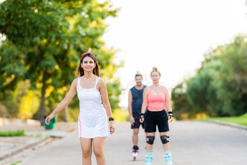 Group of Three Friends Skating with Inline Skate in a Road of a Park ...