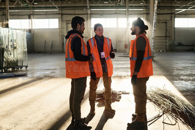 Group of Three Intercultural Builders in Workwear Discussing Working ...