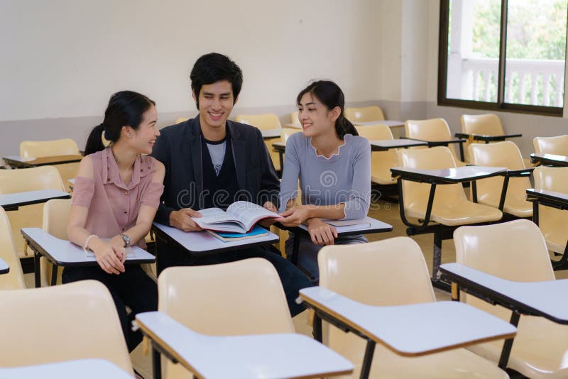 Group of Three Students Reading Book Together in Classroom Stock Photo ...