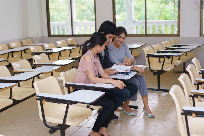 Group of Three Students Reading Book Together in Classroom Stock Image ...