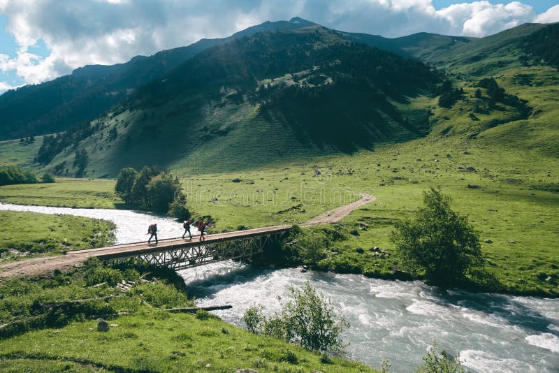 Group of Trekking Tourists Going by the Bridge Over Mountain River ...