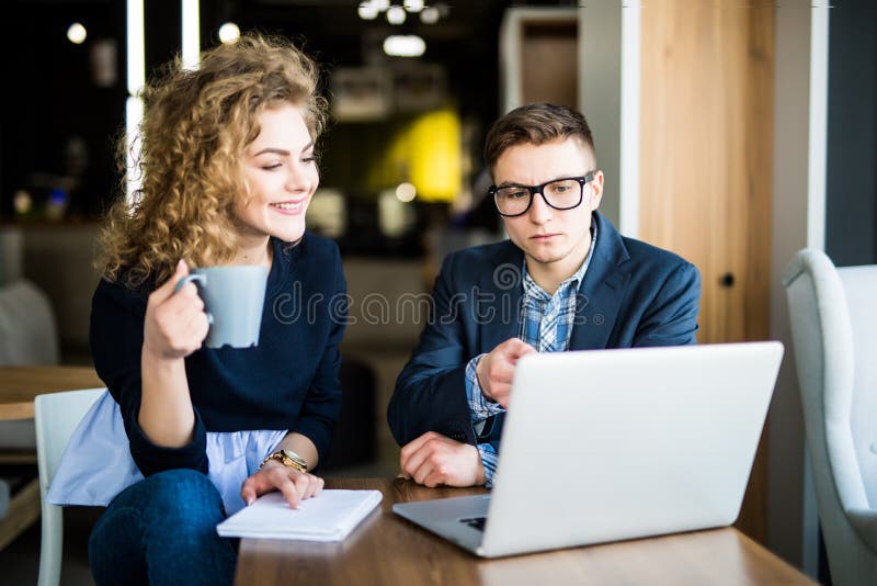 Group Of Two Coworkers Working Over Laptop Discuss In A Modern Office
