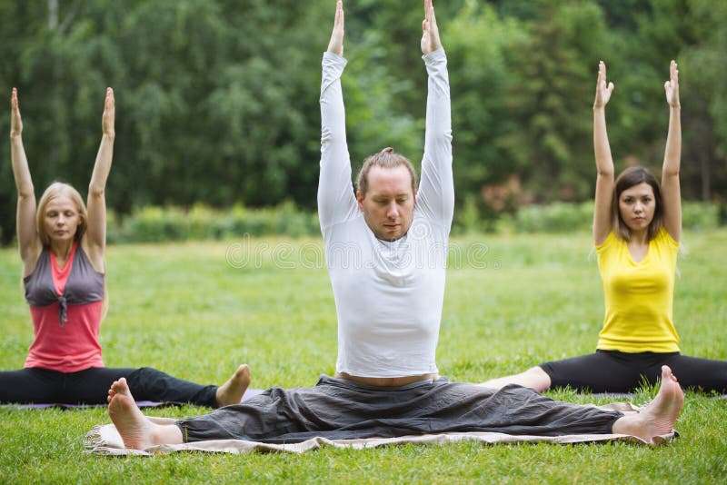 Group Yoga Practice with an Instructor on Green Grass in the Park Stock ...