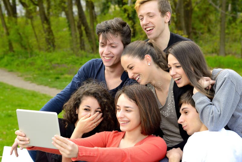 Group of Young Adults Browsing a Tablet Outside Stock Image - Image of ...