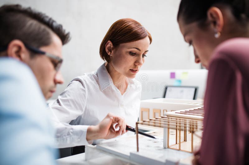Group of Young Architects with Model of a House Standing in Office ...