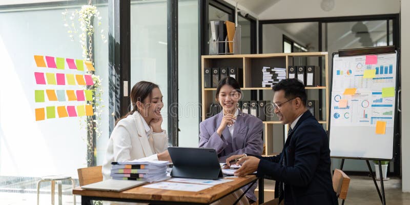 Group of Young Asian Business People Brainstorming, Looking at Laptop ... Group of Young Asian Business People Brainstorming, Looking at Laptop ...