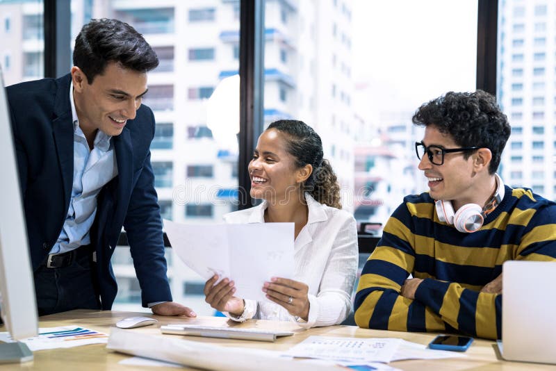 A Group of Young Business People Working Together while Sitting at ... A Group of Young Business People Working Together while Sitting at ...