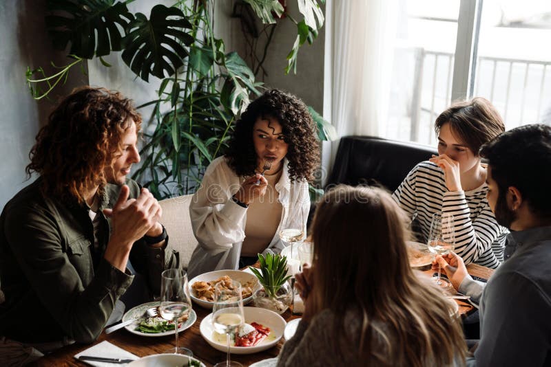 Group of Cheerful Friends Talking while Dining in Restaurant Stock ...