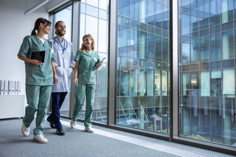 Group of Young Doctors in Lab Coats Walking in the Clinic Corridor and ...