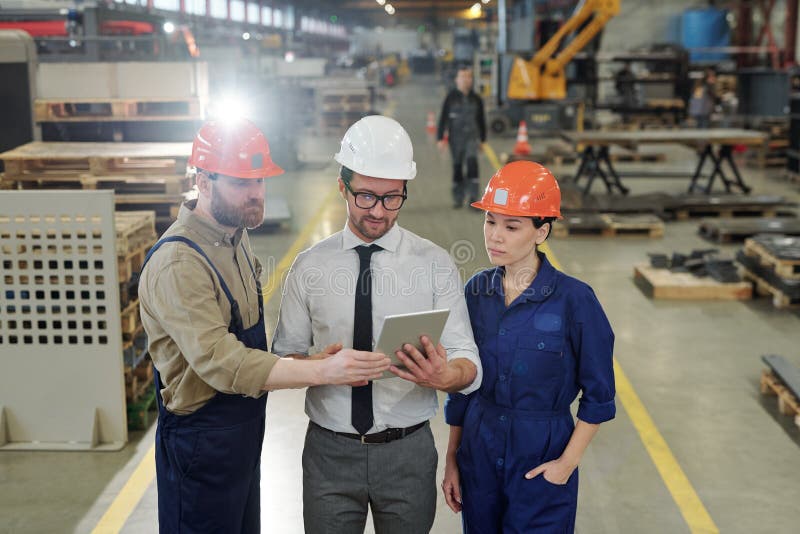 Group of Young Engineers Looking at Technical Data on Tablet Display ...