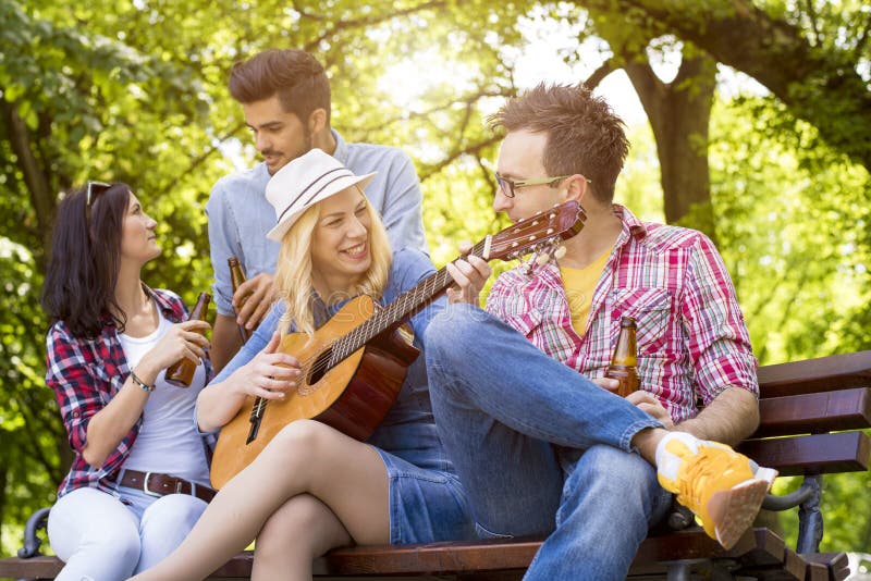 Group of Young Friends Playing Guitar and Drinking Beers on a Park ...
