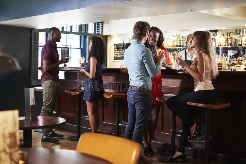 Group of Young Friends Relaxing in Bar Standing at Counter Stock Image ...