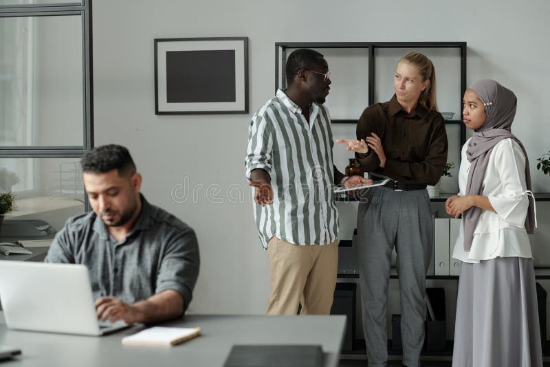 Group of Young Multicultural Colleagues Talking about Coworker Behind ...