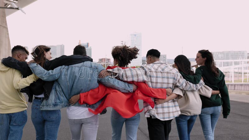 Group Of Young Multiracial Friends Hugging Each Other While Walking