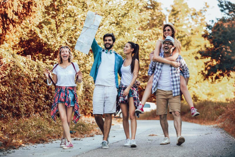 Young People with Backpacks Walking Together by the Road and Looking ...