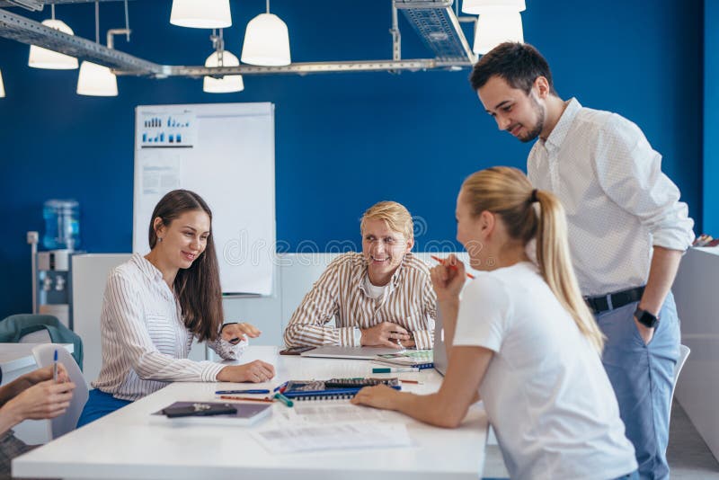 Group of Young People Gather Around Table and Talk while they Work ...