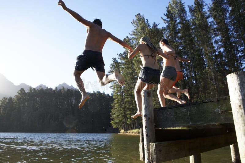 Group of Young People Jumping from Jetty into Lake Stock Image - Image ...