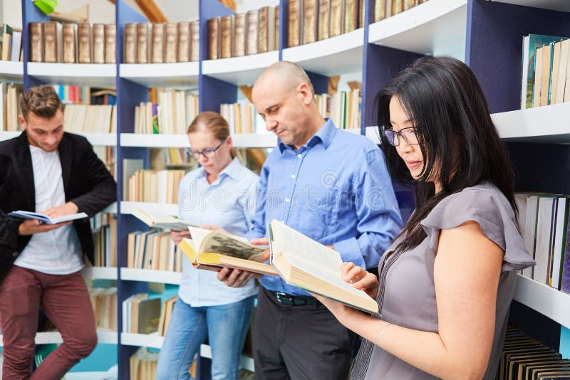 Group of Young People in the Library while Reading Book Stock Photo ...