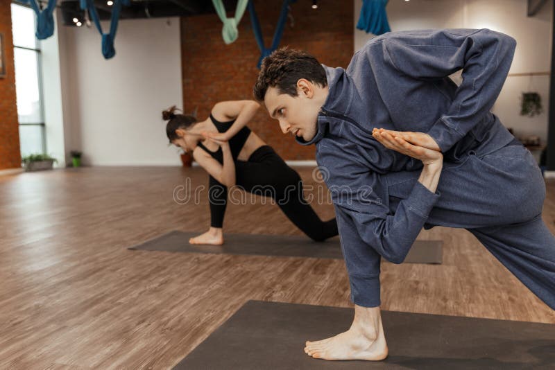 Group of Young People Practising Yoga with Trainer in Yoga Spacious ...