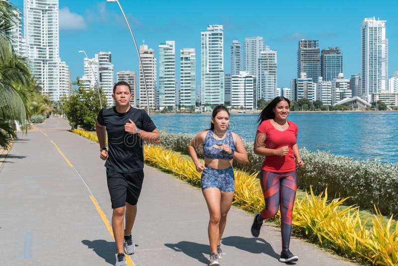 Group of Young People Running through the Park between Green Trees and ...