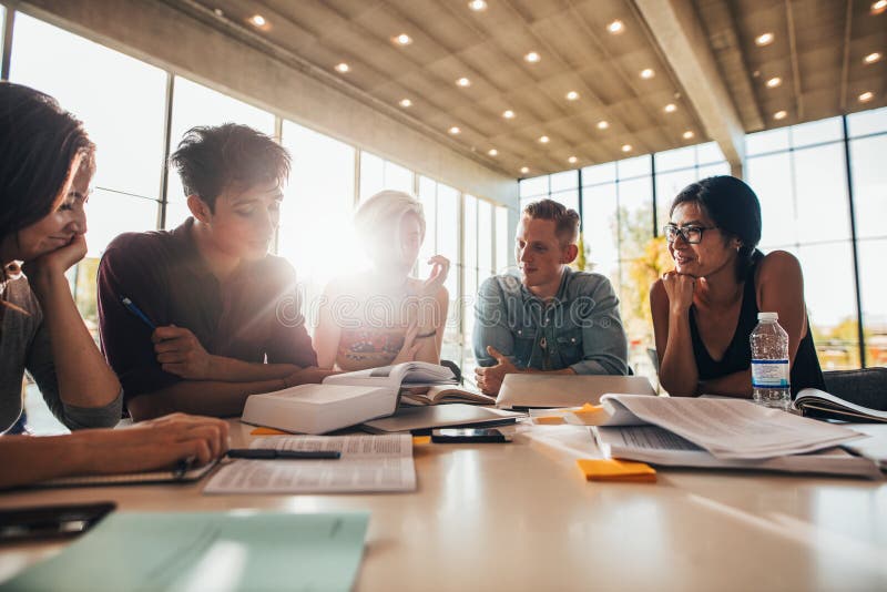 Group of Young People Sitting at Table Reading Books Stock Photo ...