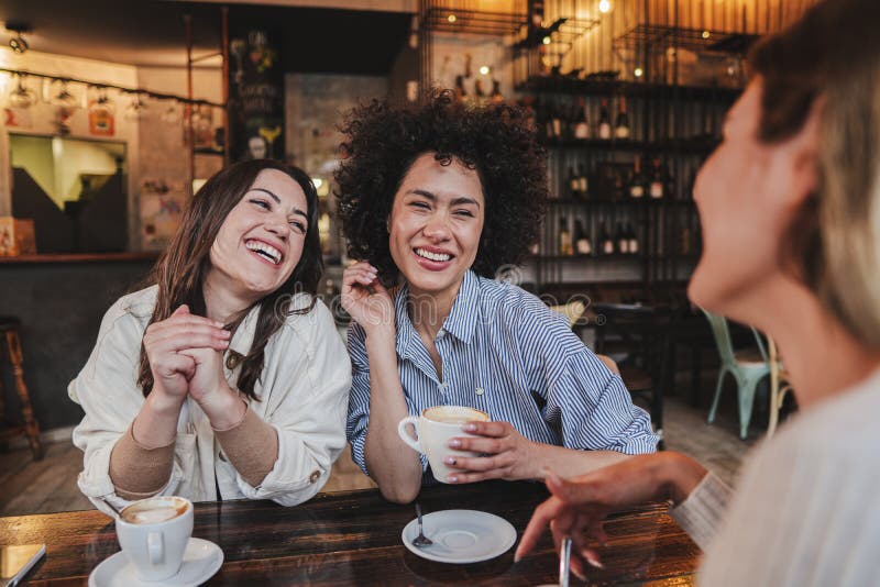 A Group Of Young Women Talking And Laughing Sitting On A Coffee Shop Or