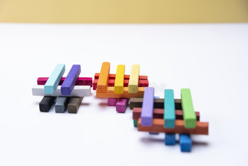 GROUPS of COLORED CHALKS in PILES on a WHITE and YELLOW BACKGROUND ...