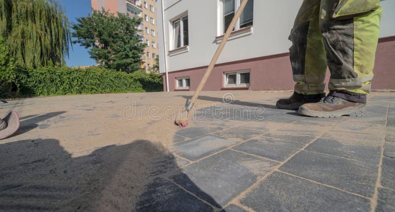 Sweeping Sand into the Joints of a Yard Paved with Paving Stones. Stock ...