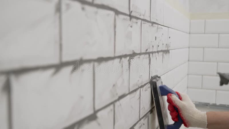 Workers Hands Using a Rubber Spatula and Grouting with Paste between ...