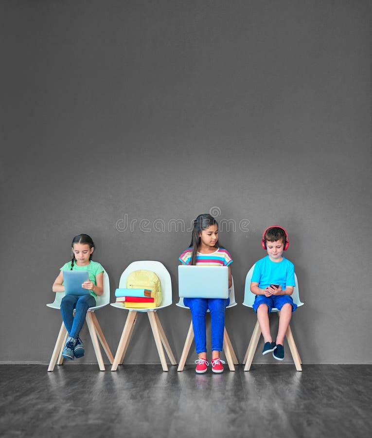 Growing Up with Wireless Gadgets. Studio Shot of Kids Sitting on Chairs ...