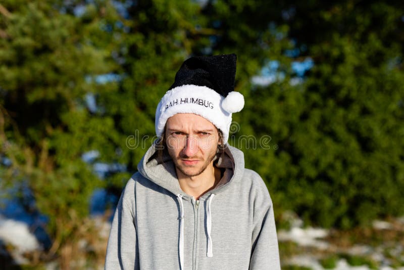 A Grumpy Young Man Wearing a Black Santa Hat with the Words Bah Humbug ...