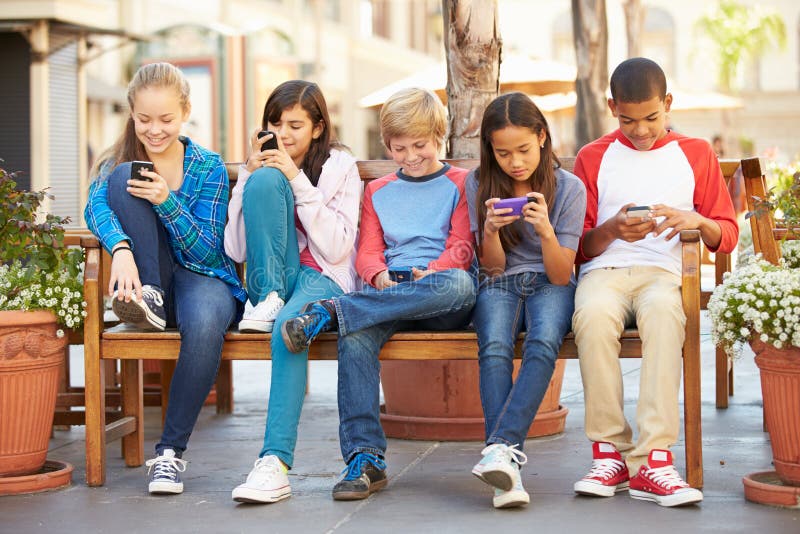 Grupo De Crianças Que Sentam Se Na Alameda Usando Telefones Celulares