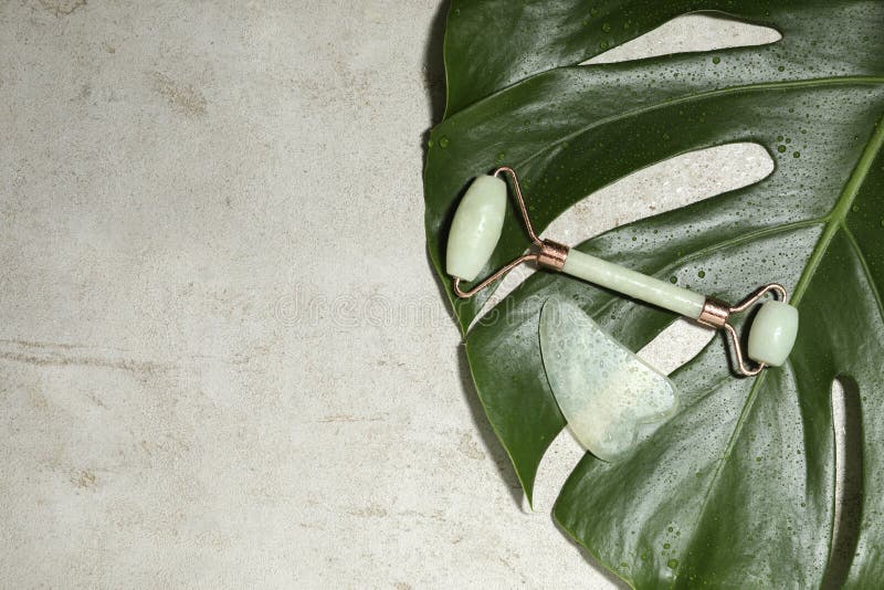 Gua Sha Stone, Face Roller and Monstera Leaf on Light Table, Flat Lay ...