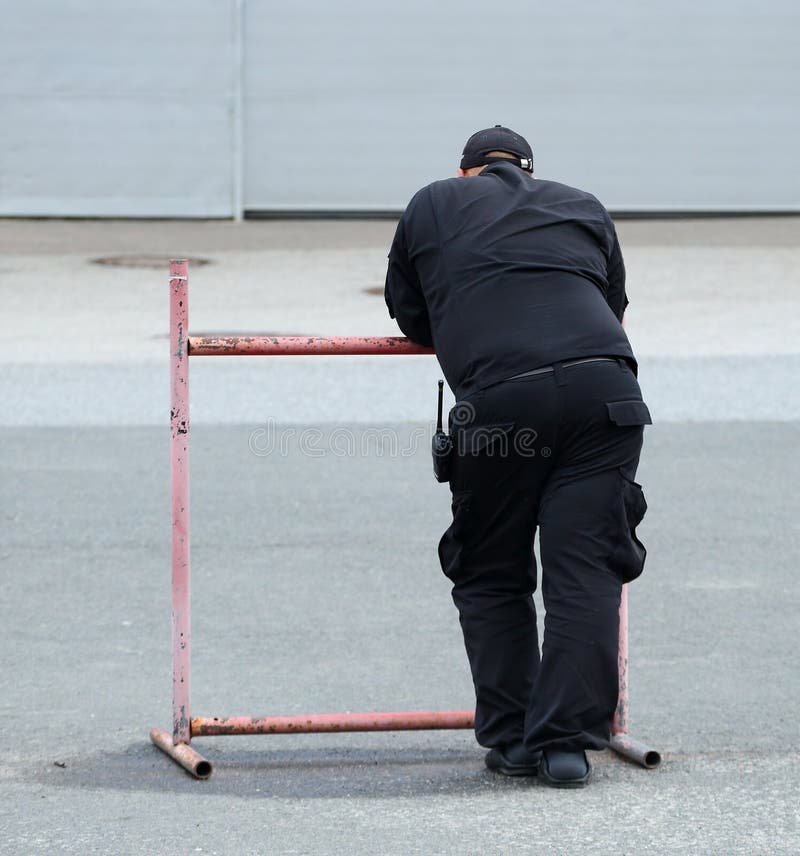 Guard in a Black Uniform Leans Against a Metal Barrier Stock Photo ...