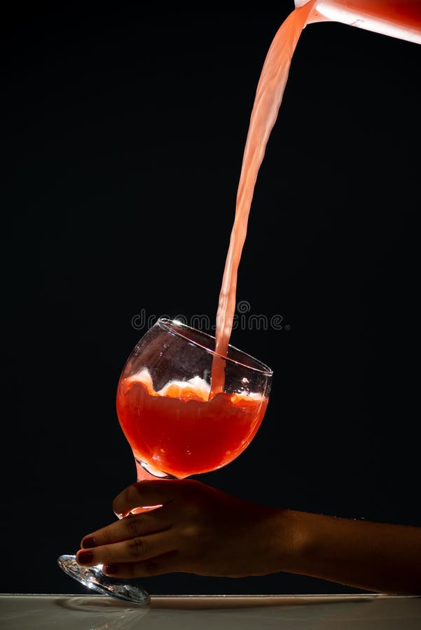 Guava Juice Falling from a Plastic Container into a Glass Cup Held by a ...