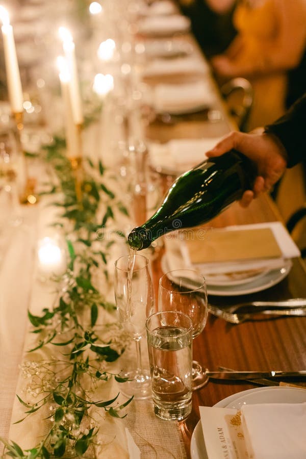 Elegant Dinner Setting with Candlelight and Sparkling Wine Being Poured ...