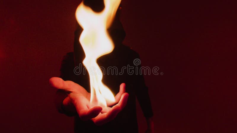 The Guy in the Black Robe Holds a Burning Hand with Real Fire in Front ...