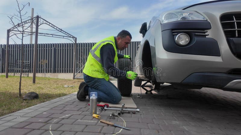 A Guy Changes Tire on Street To Summer Tire in Nature Stock Footage ...