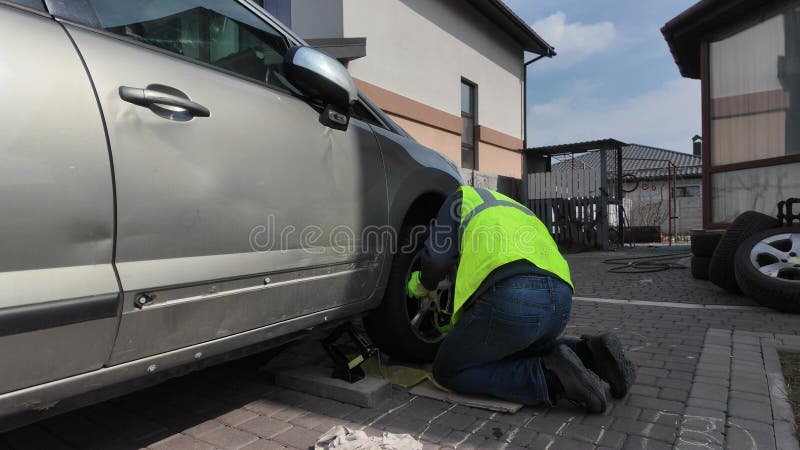 A Guy Changes Tire on Street To Summer Tire in Nature Stock Footage ...
