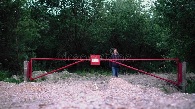The Guy Goes Along a Dirt Road and Crawls Under a Gate with a STOP Sign ...