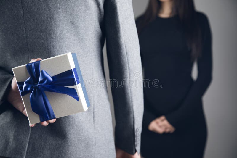 A Guy Holding a Gift from Behind while Standing in Front of a Girl ...