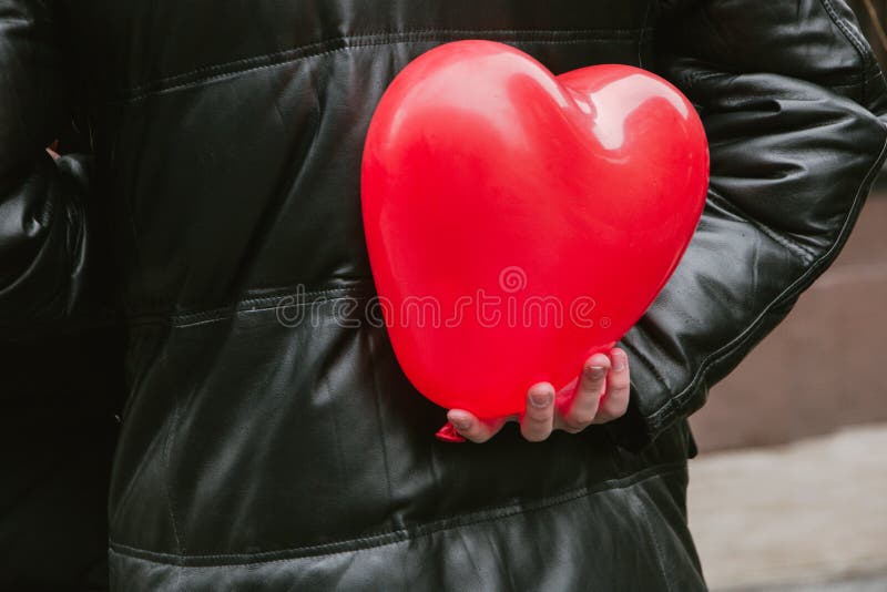 The Guy Holds a Red Heart Ball in His Hand Behind His Back Stock Photo ...